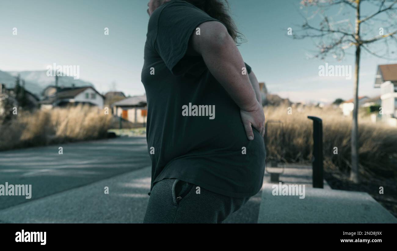 Dramatic moment of person suffering from back pain. An overweight man ...