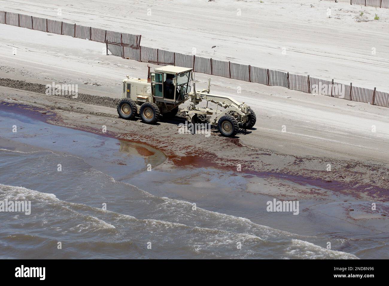 A motor grader grades a beach as oil laps onto the shore on Elmer's ...