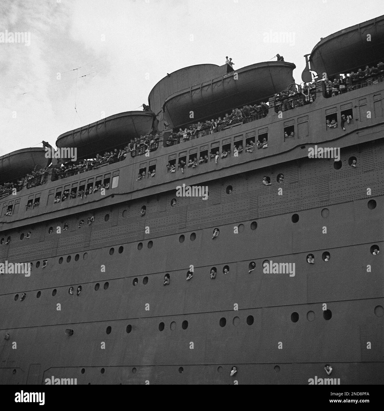U.S. troops crowd the decks and portholes of the huge British liner ...