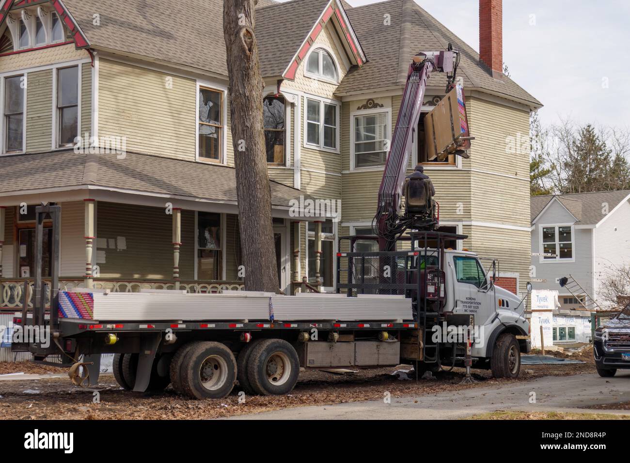 Workers using crane to load drywall through second story window of ...