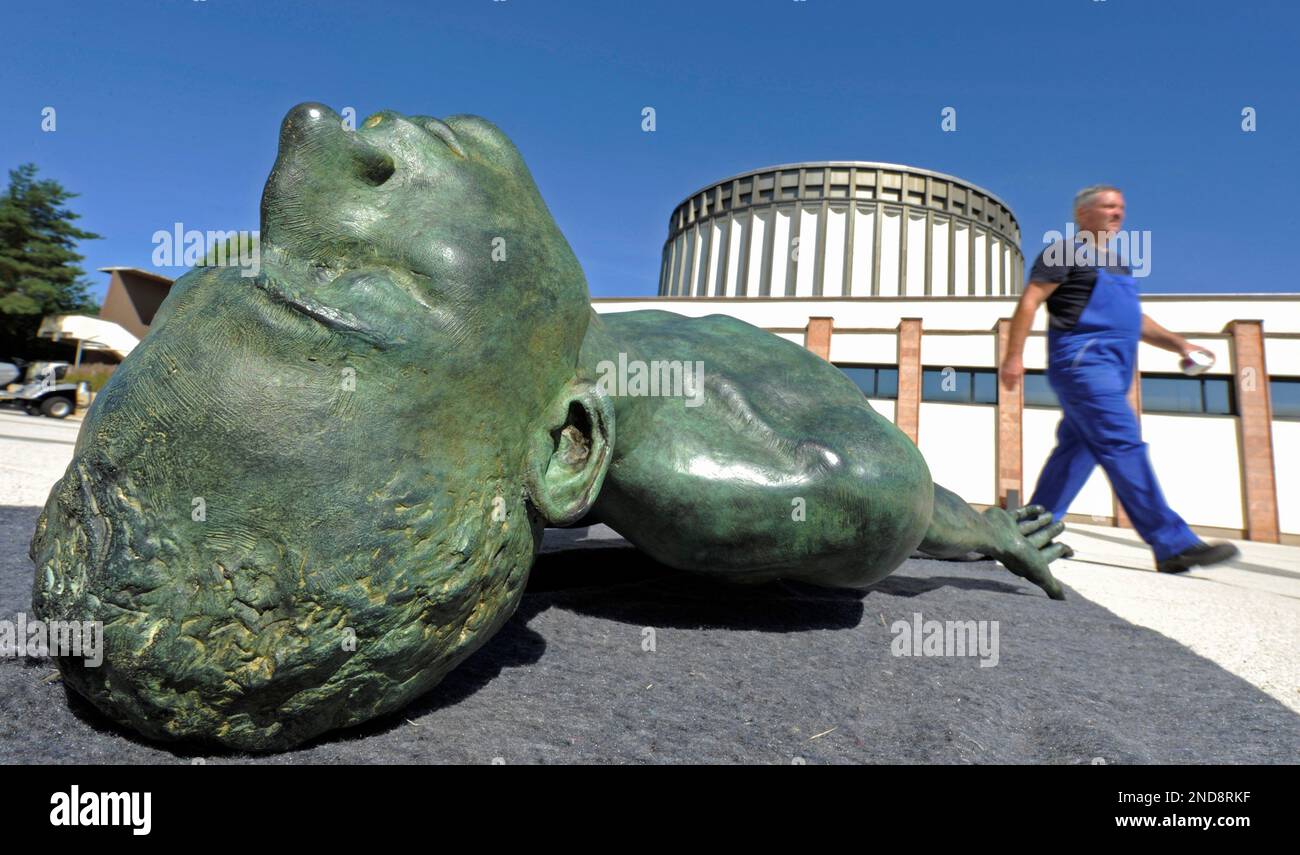 A worker walks besides the bronze sculpture 'I am Here Now' of Dutch ...
