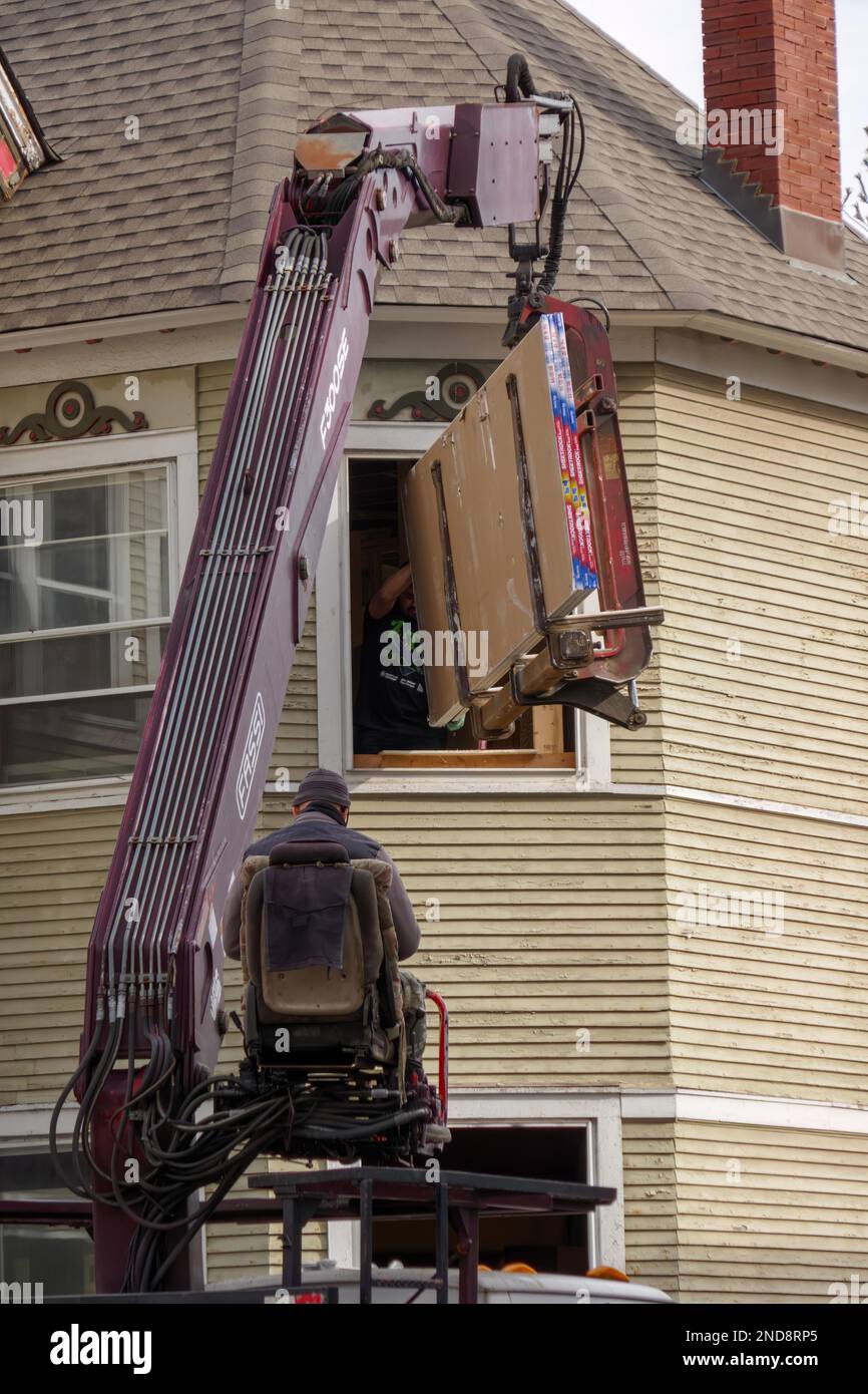 Workers using crane to load drywall through second story window of ...