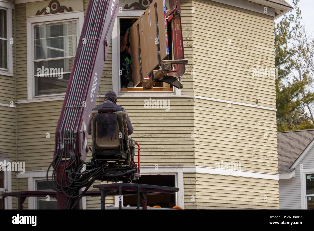 Workers using crane to load drywall through second story window of ...