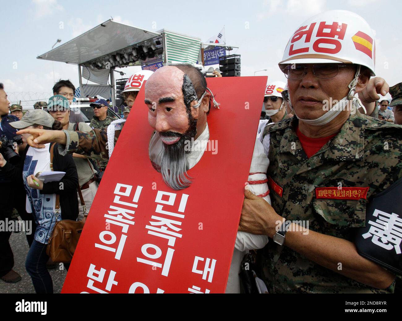 South Korean Vietnam War veterans detain a man playing the role of the ...
