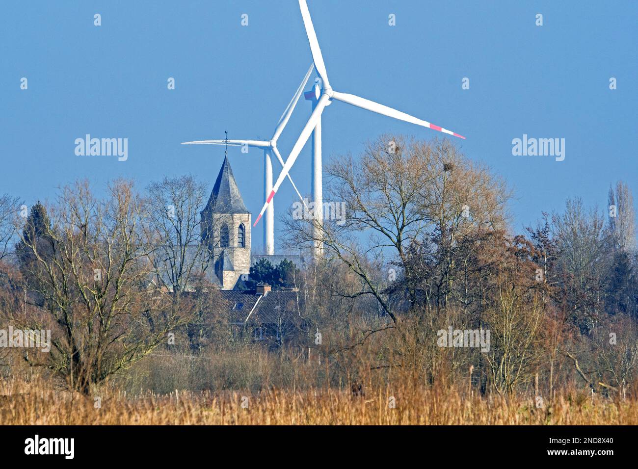 Church tower of the village Mariakerke near Ghent and wind turbines ...