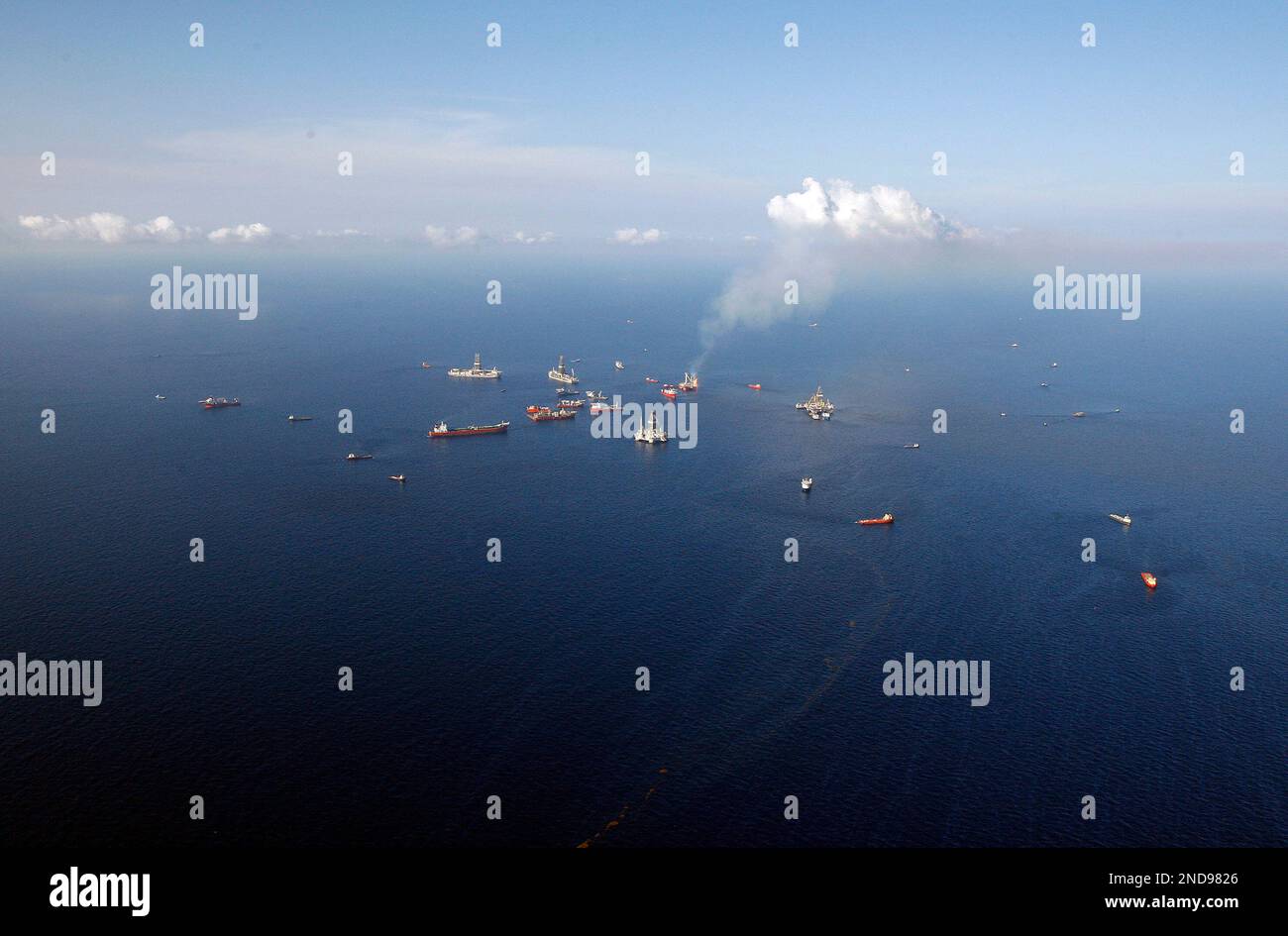 Streaks of oil float near vessels assisting in the capping of the ...