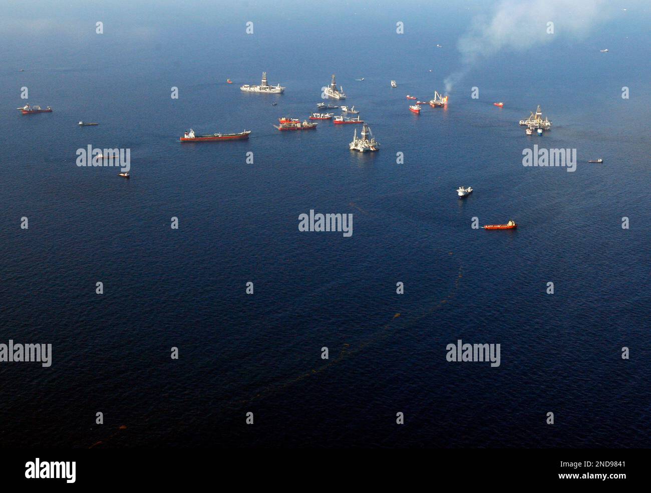 Streaks of oil float near vessels assisting in the capping of the ...