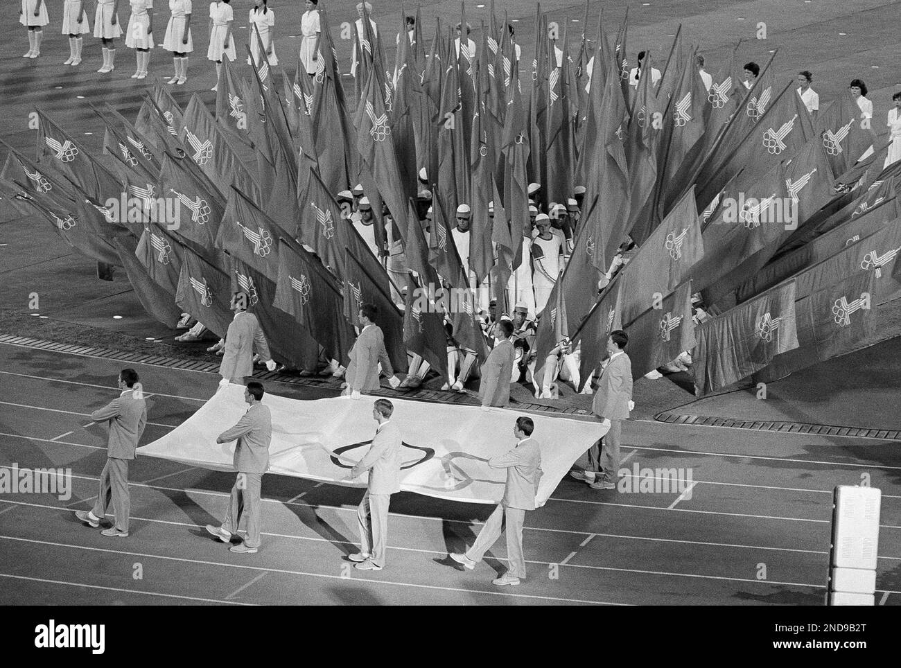 Soviet athletes carry the Olympic banner past a bevy of flags bearing ...
