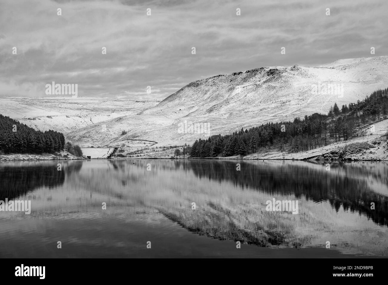 Snow covered Dovestone Reservoir and reflection of a landscape in its ...
