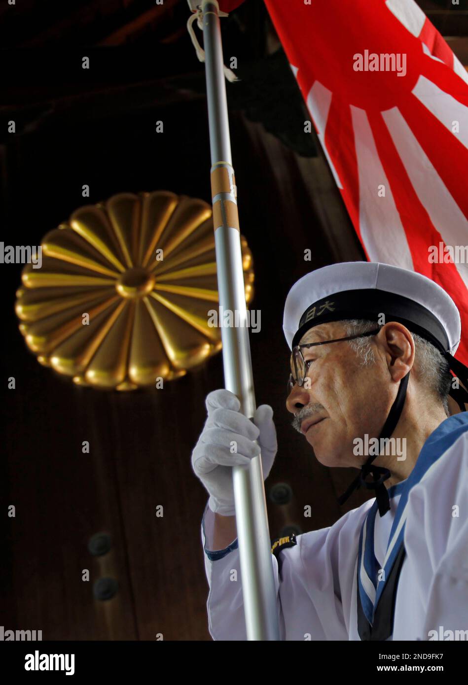 A man wearing a Japanese Imperial navy uniform carries a rising sun ...