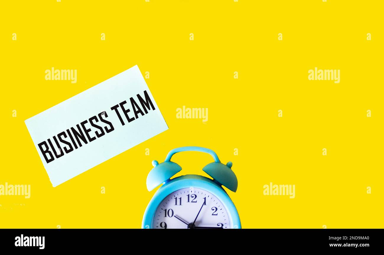 BUSINESS TEAM text on sticker and yellow background with clock ...