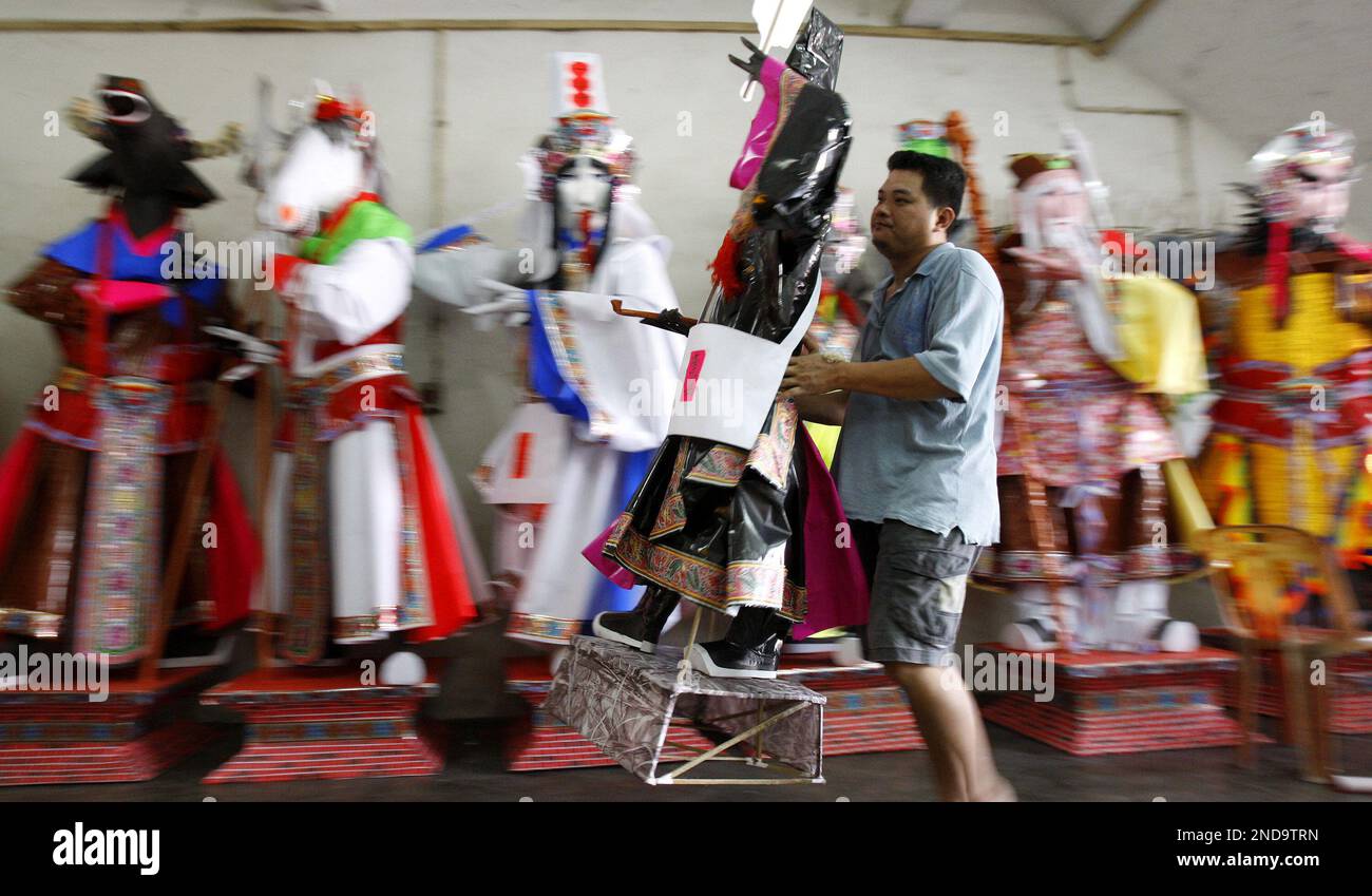 Malaysian craftsman Tan Chee Ooi carries a paper offering statue in ...