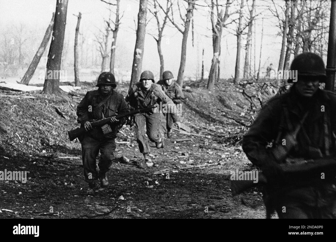 U.S. troops make a dash across a tree-lined road under machine gun fire ...