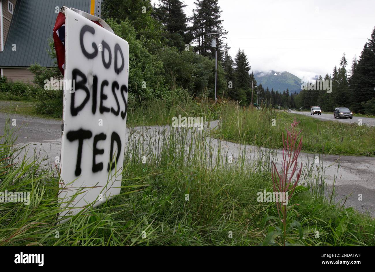 A spray-painted roadside sign that reads "God Bless Ted," is shown ...