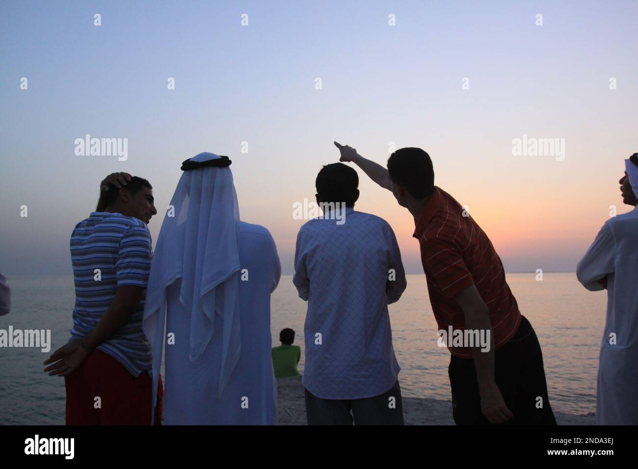 Bahraini men scan the sky at dusk Wednesday, Aug. 11, 2010, in the ...