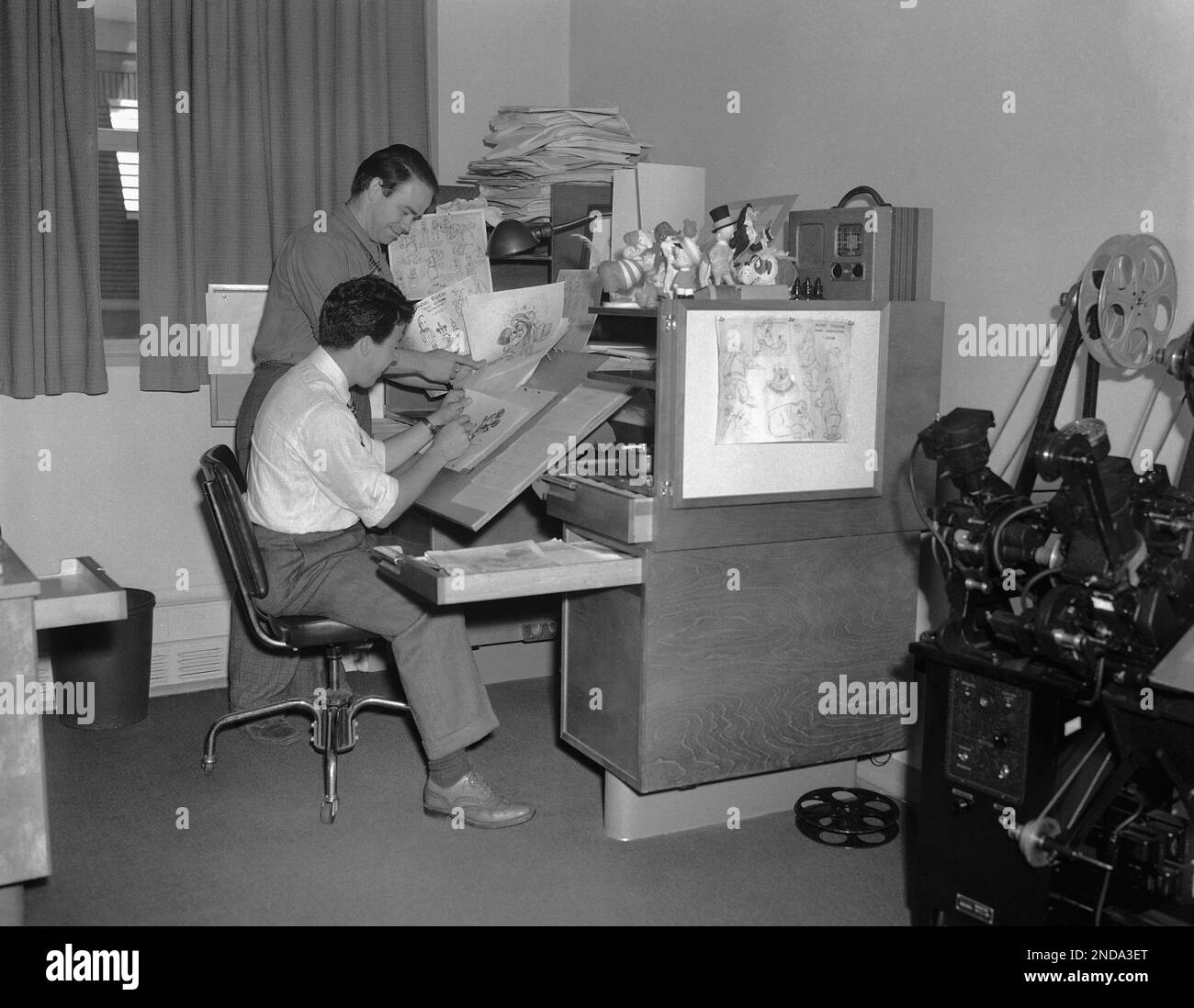 Ward Kimball, seated, and Fred Moore are shown at work at the Walt ...