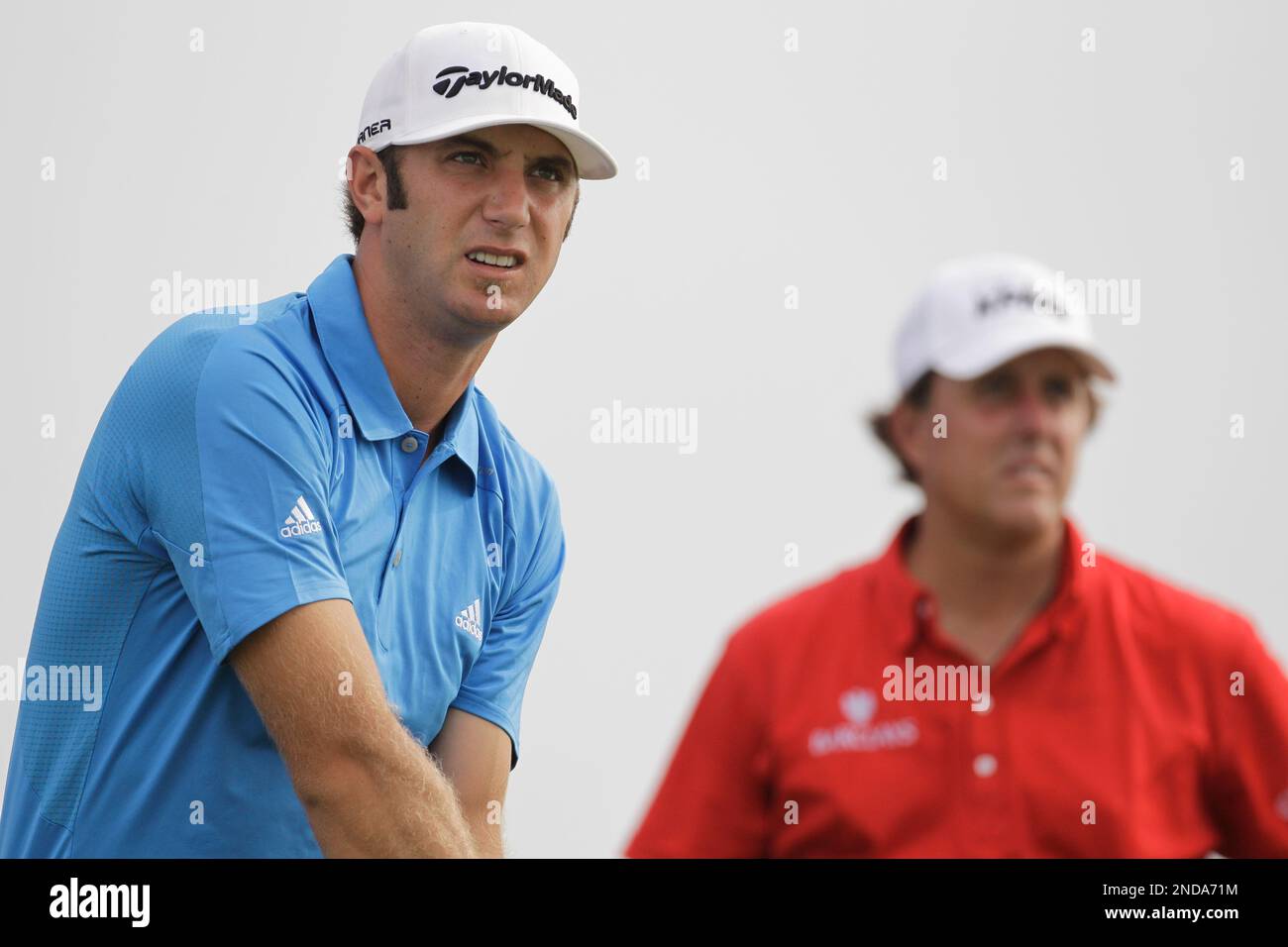 Dustin Johnson watches his drive with Phil Mickelson during a practice ...