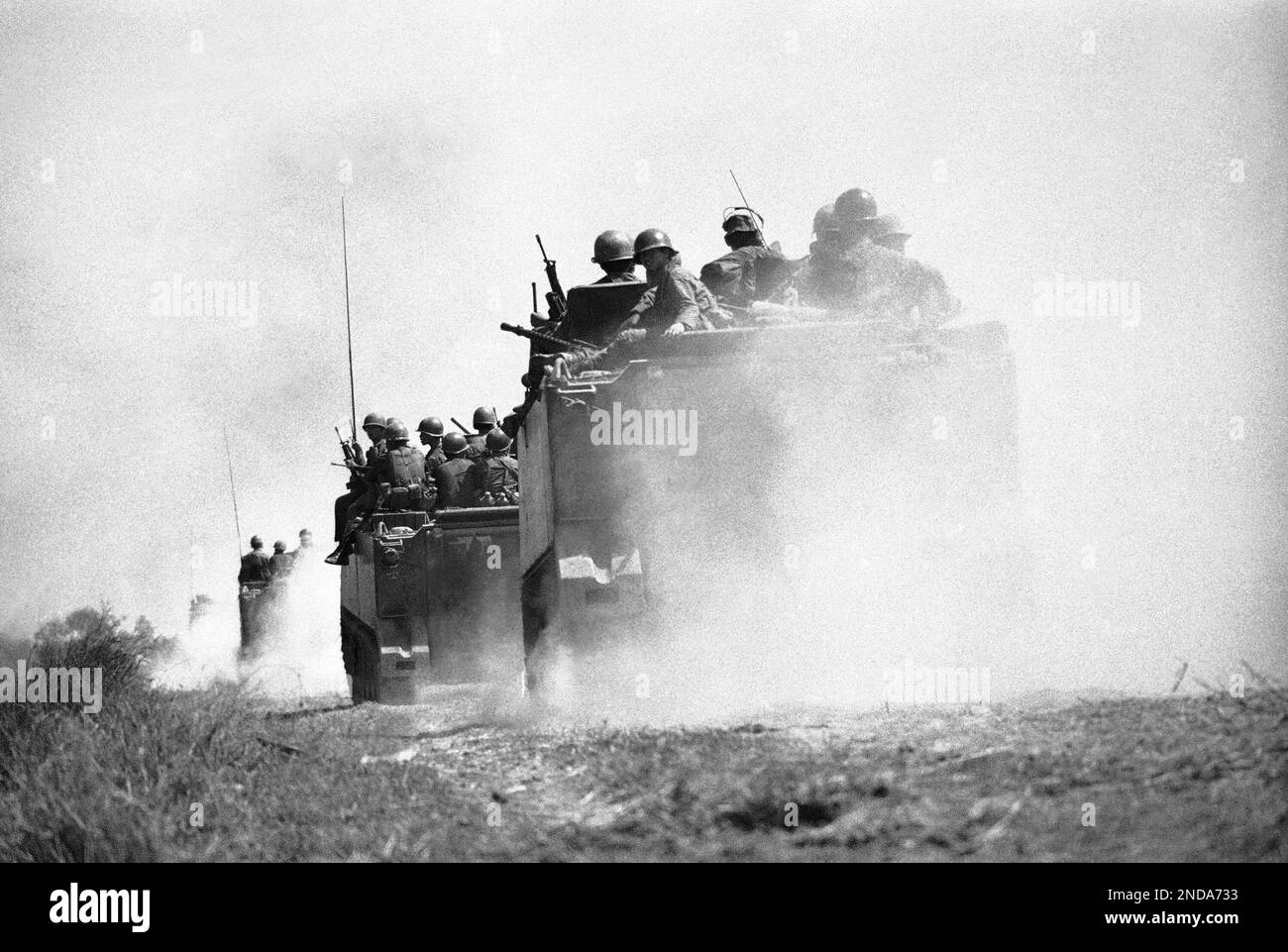 A column of South Vietnamese armored personnel carriers churns up dust ...