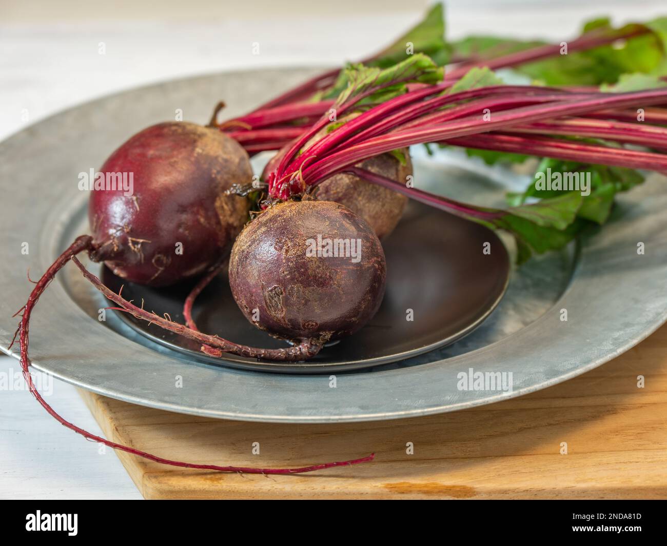 Beets with bright red stems and green leaves ready to be peeled and ...