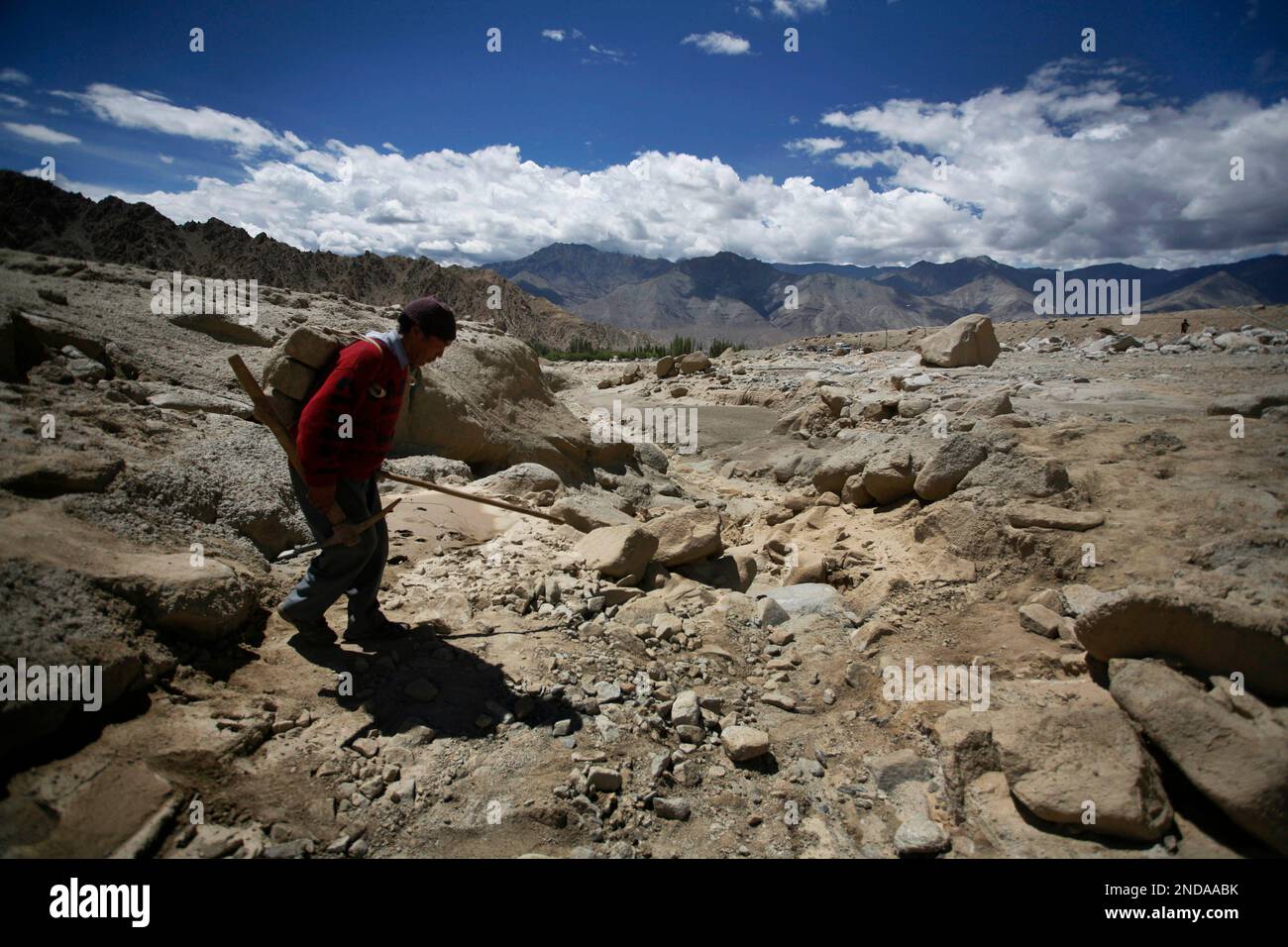 A resident carries clay bricks to construct a funeral pyre as he walks ...