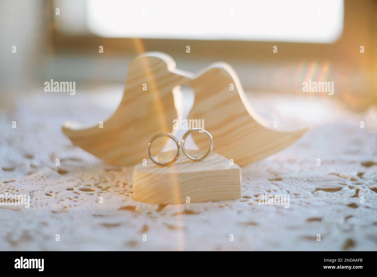 Two wooden handmade toy birds with two golden wedding rings and heart ...
