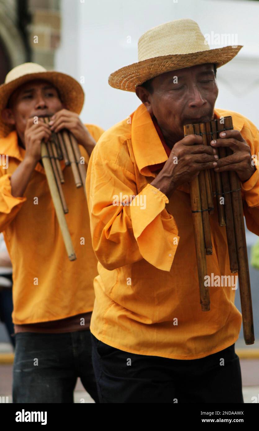 Kuna Indigenous men blow reed flutes as they dance during a ...