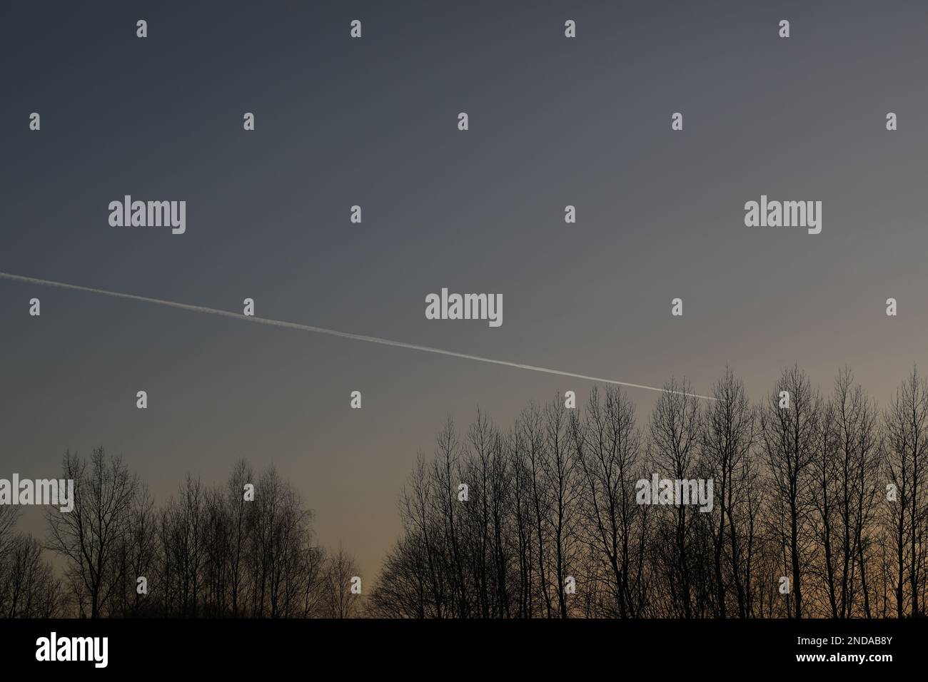 airplane flies in sunset sky and leaving trail. Amazing panoramic ...