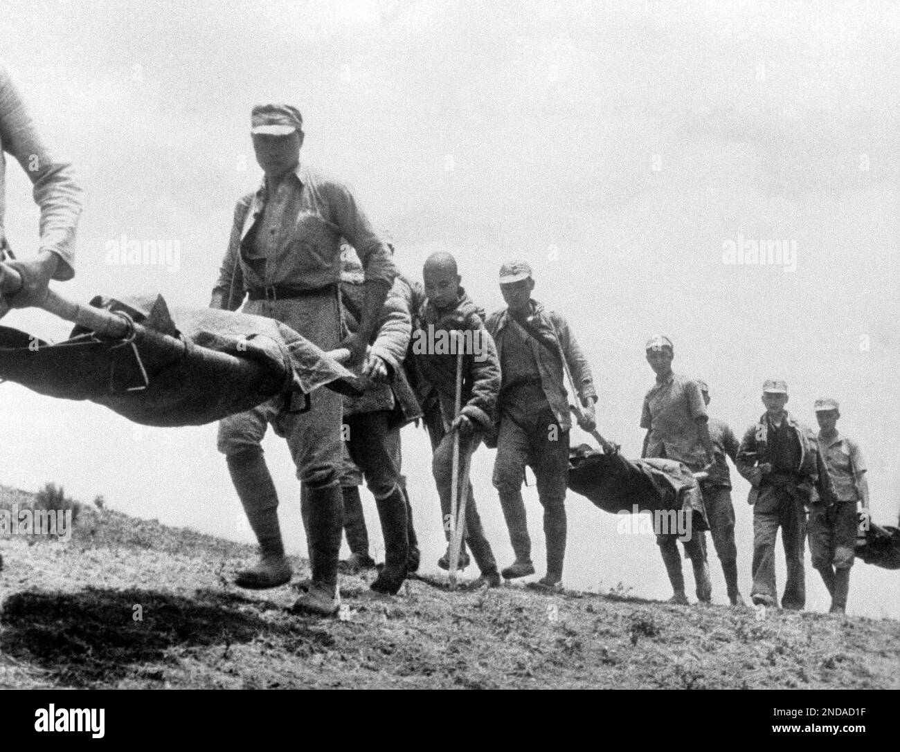 A line of wounded Chinese soldiers, interspersed with stretcher bearers ...