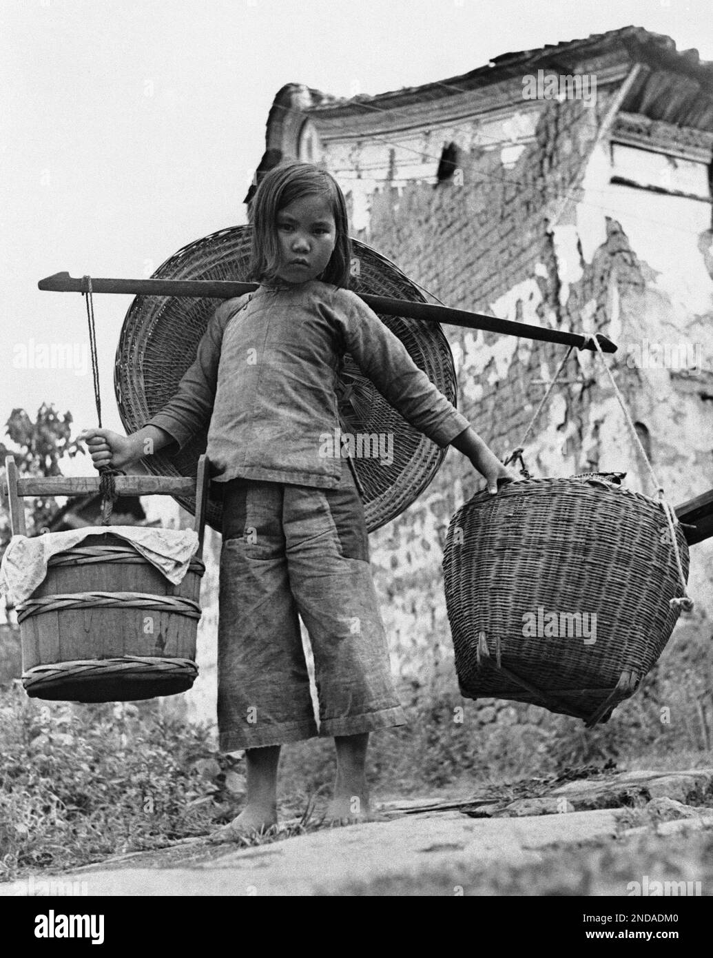 A young Chinese refugee carries family belongings as she returns to her ...