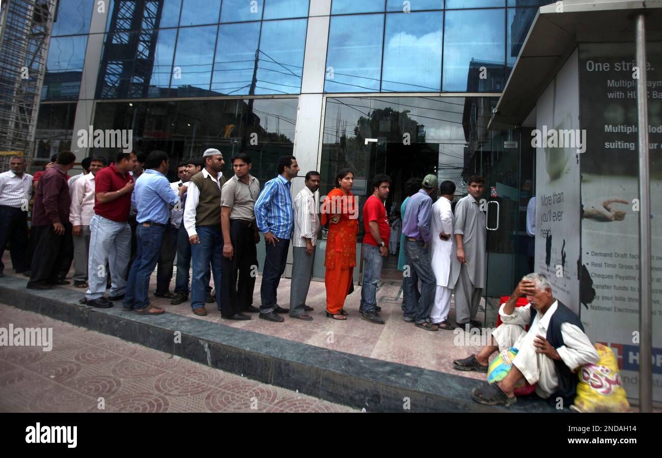 A Kashmiri man sitting on a pavement holds his head as people wait in a ...