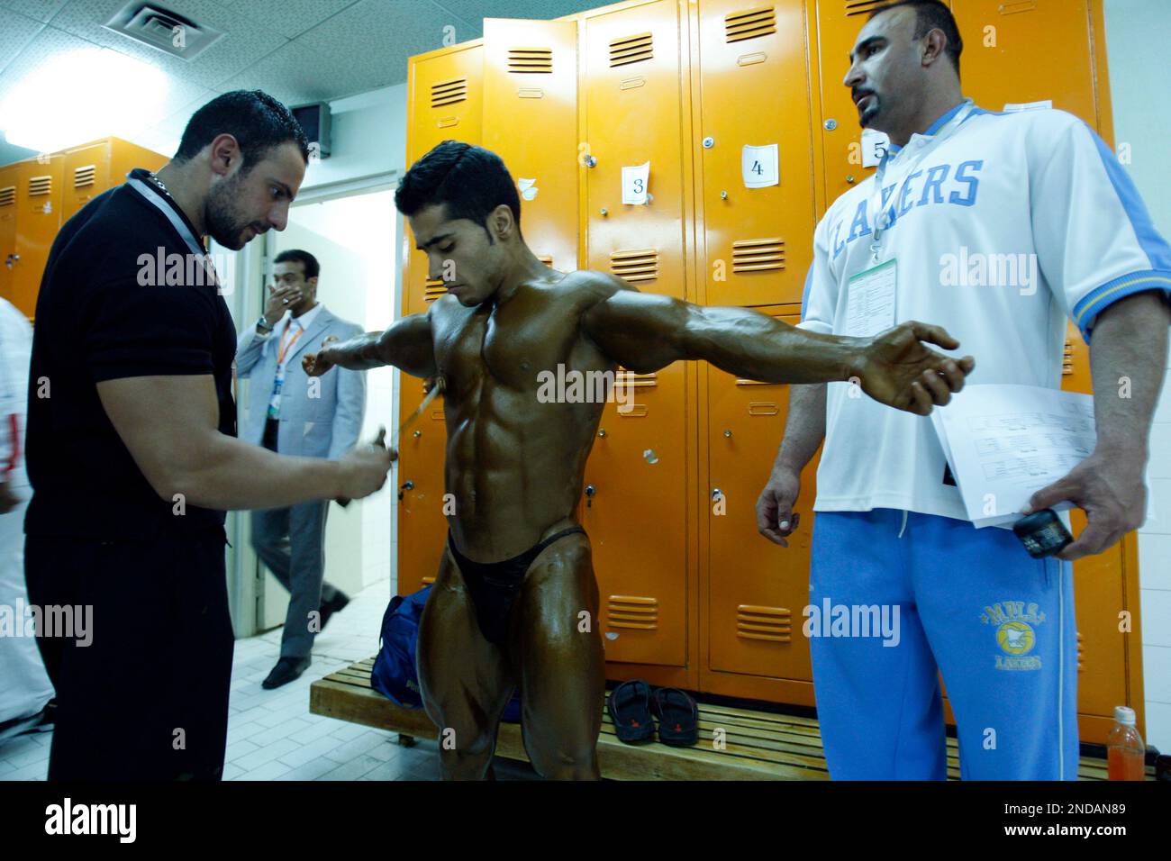An unidentified man, colors the body of Iranian bodybuilder Mehdi ...