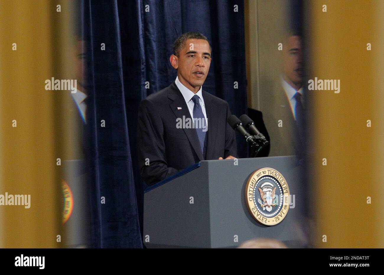 President Barack Obama is reflected in a mirror as he speaks to members ...