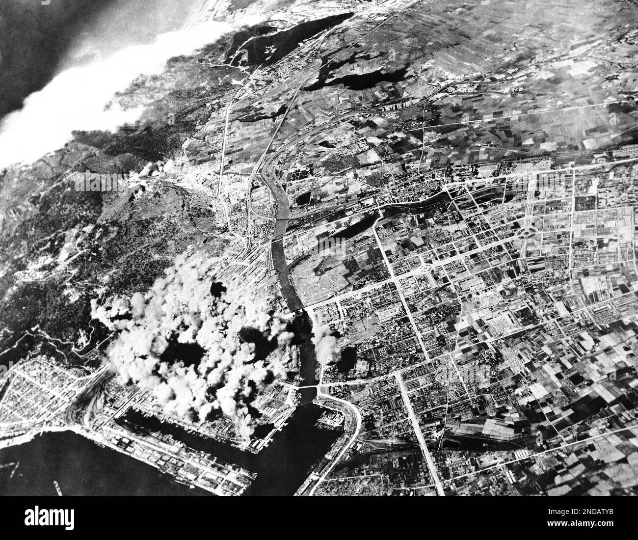 Bombs from a Fifth Air Force squadron fall on a Japanese war plant ...