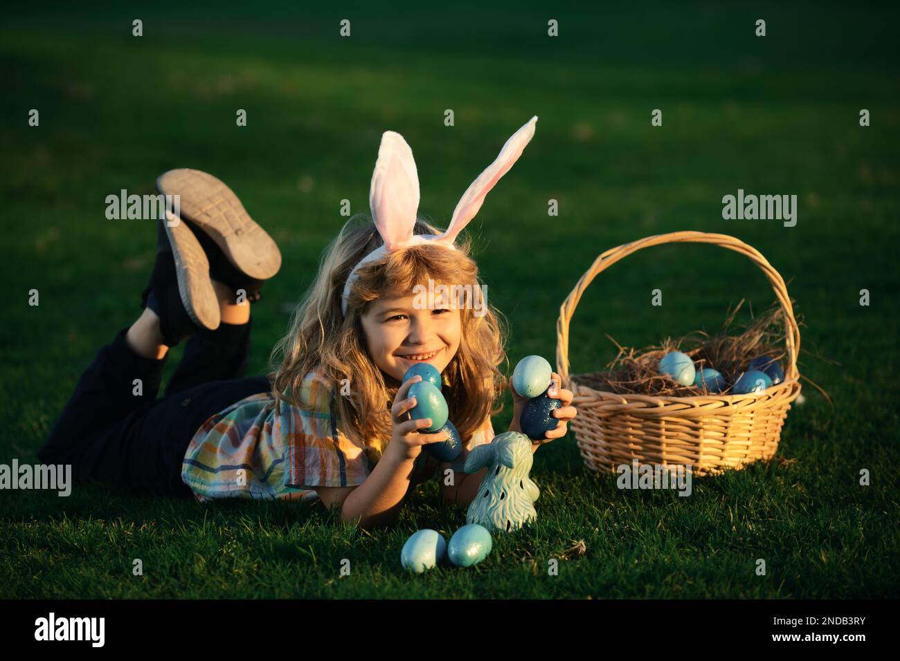 Children hunting easter eggs. Kid boy lying on the grass and finding ...
