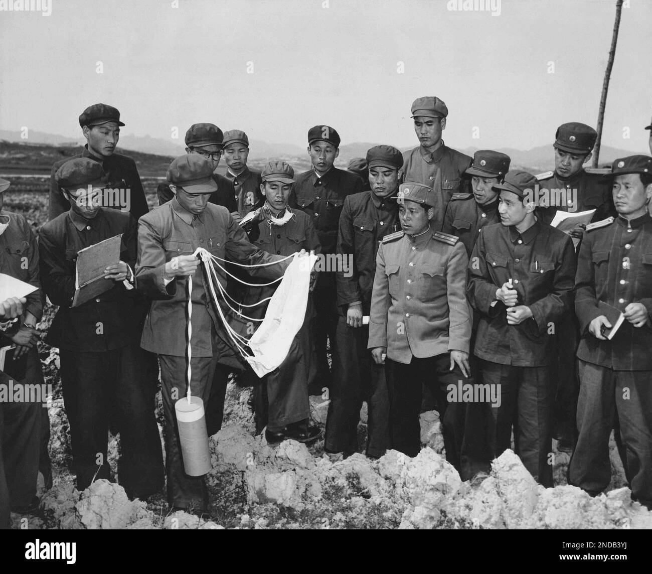 Communist personnel inspect the parachute flare at the scene of the ...