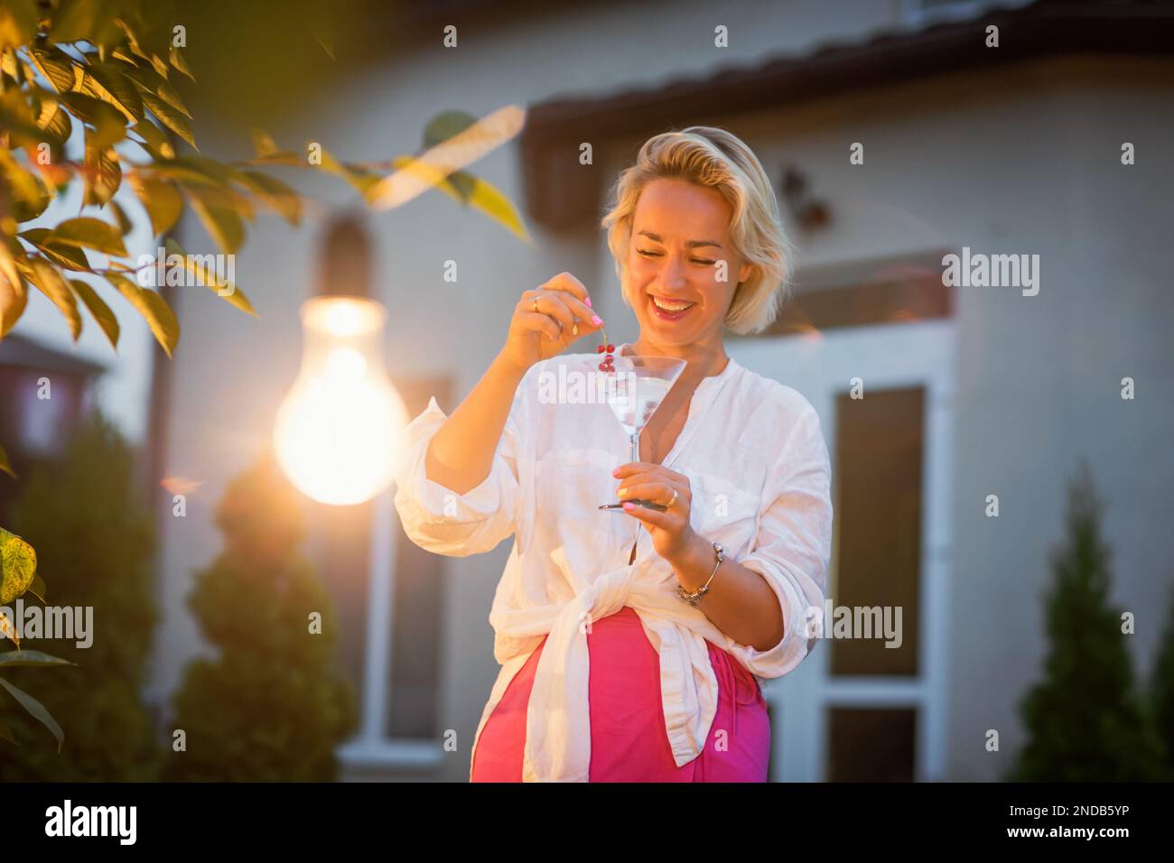 Young blonde woman drinking dry martini in the backyard Stock Photo - Alamy