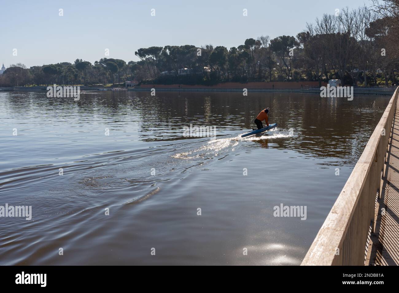 Anonymous traveler floating on rippling lake water on boat near wooden ...