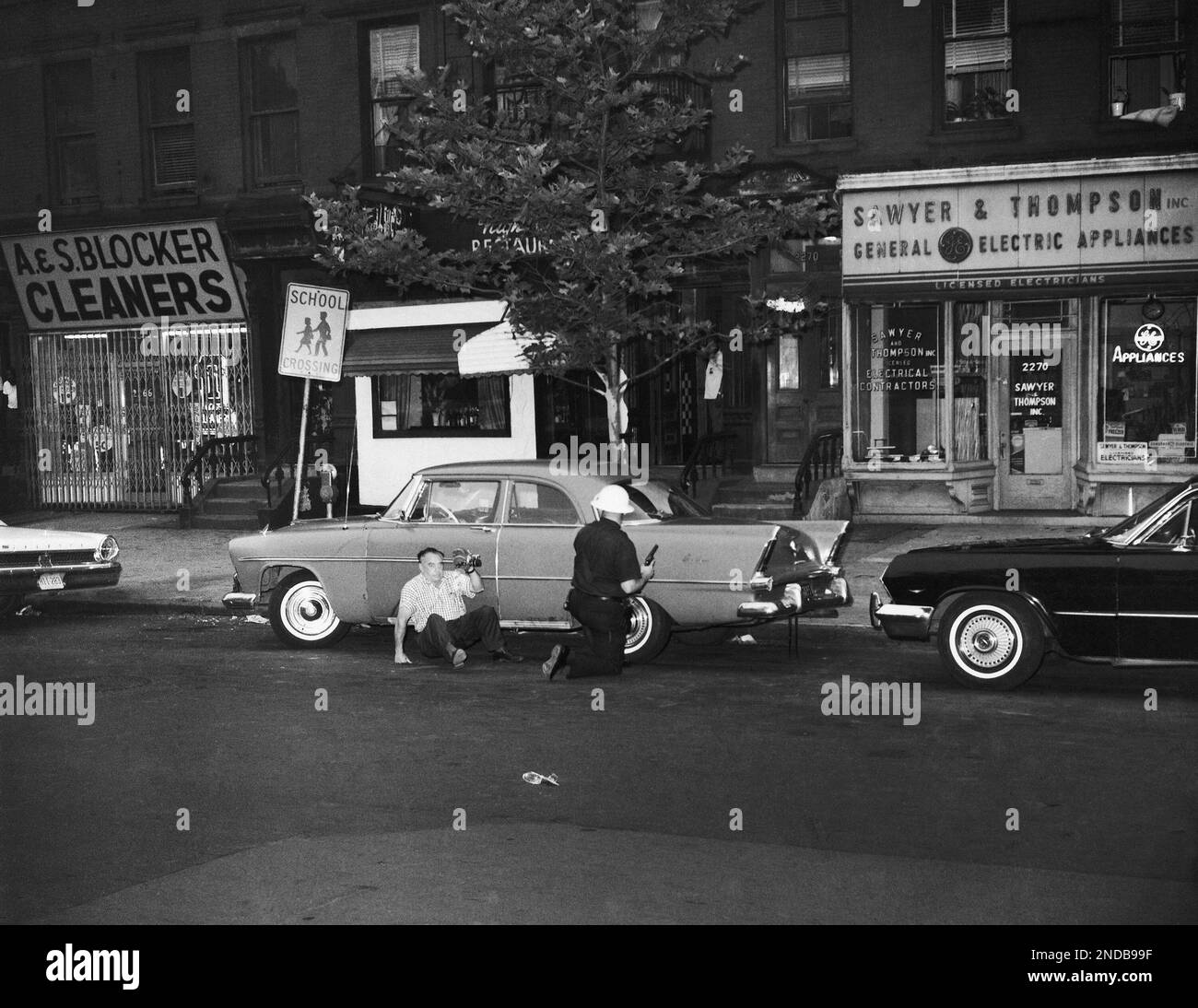 A movie cameraman sprawls on street pavement next to a helmeted, pistol ...