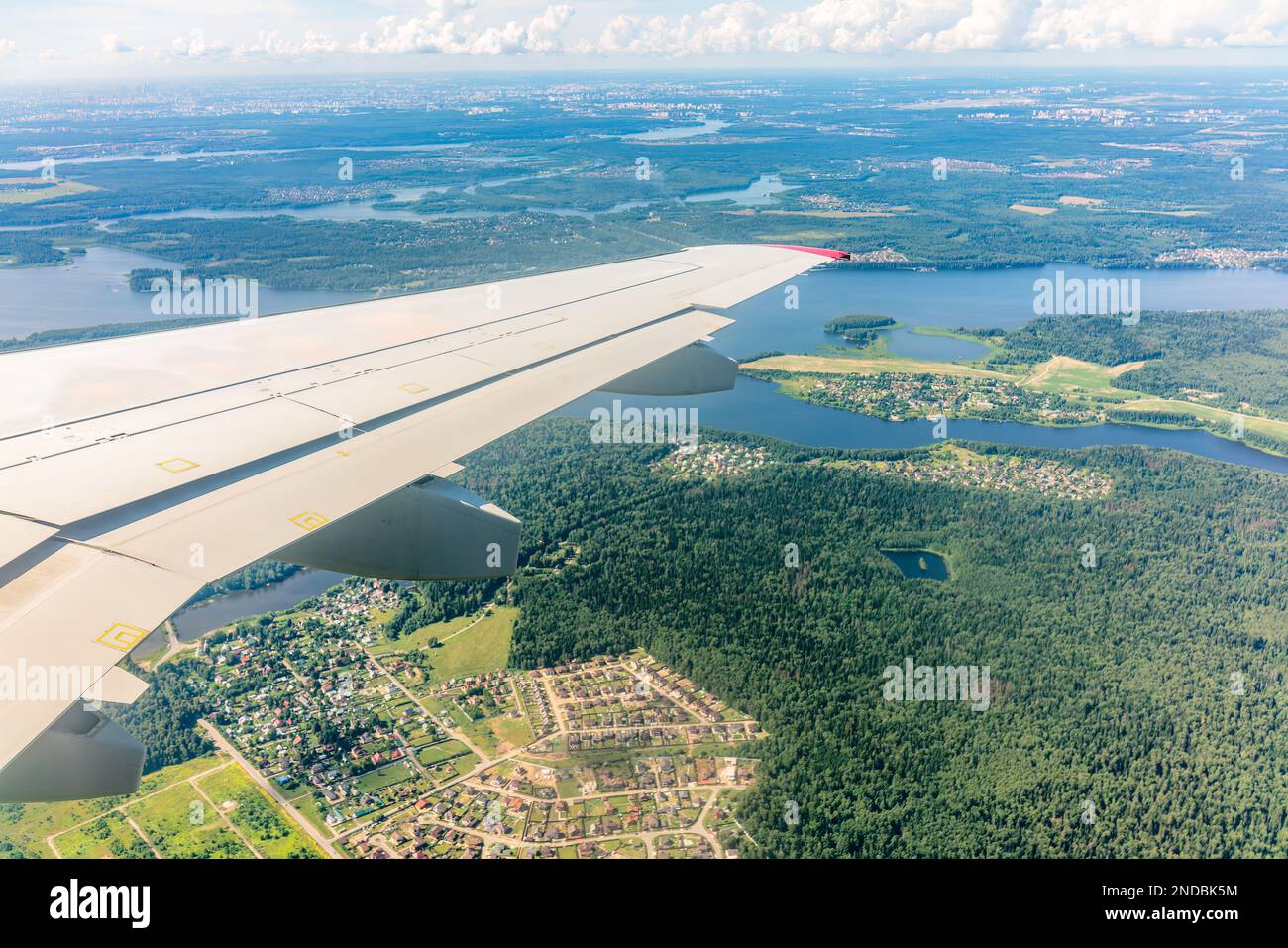 View of airplane wing, blue skies and green land during landing ...
