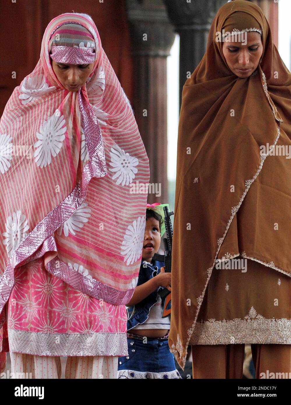 A child plays with a toy gun as elders offer Friday prayers at the Jama ...