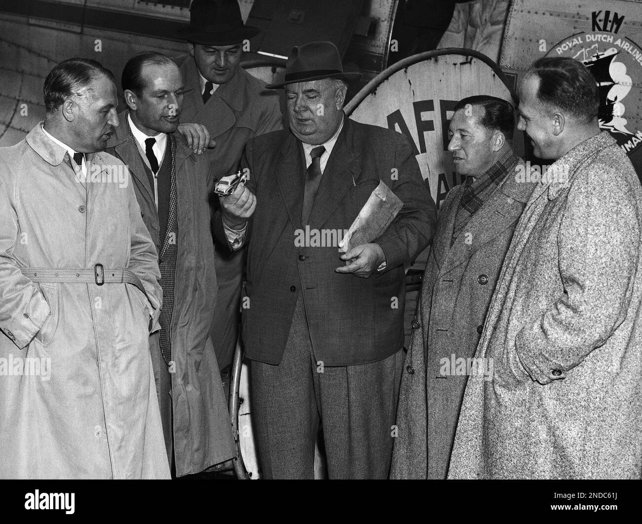 Alfred Neubauer, center, coach of the Mercedes racing team holds a tiny ...