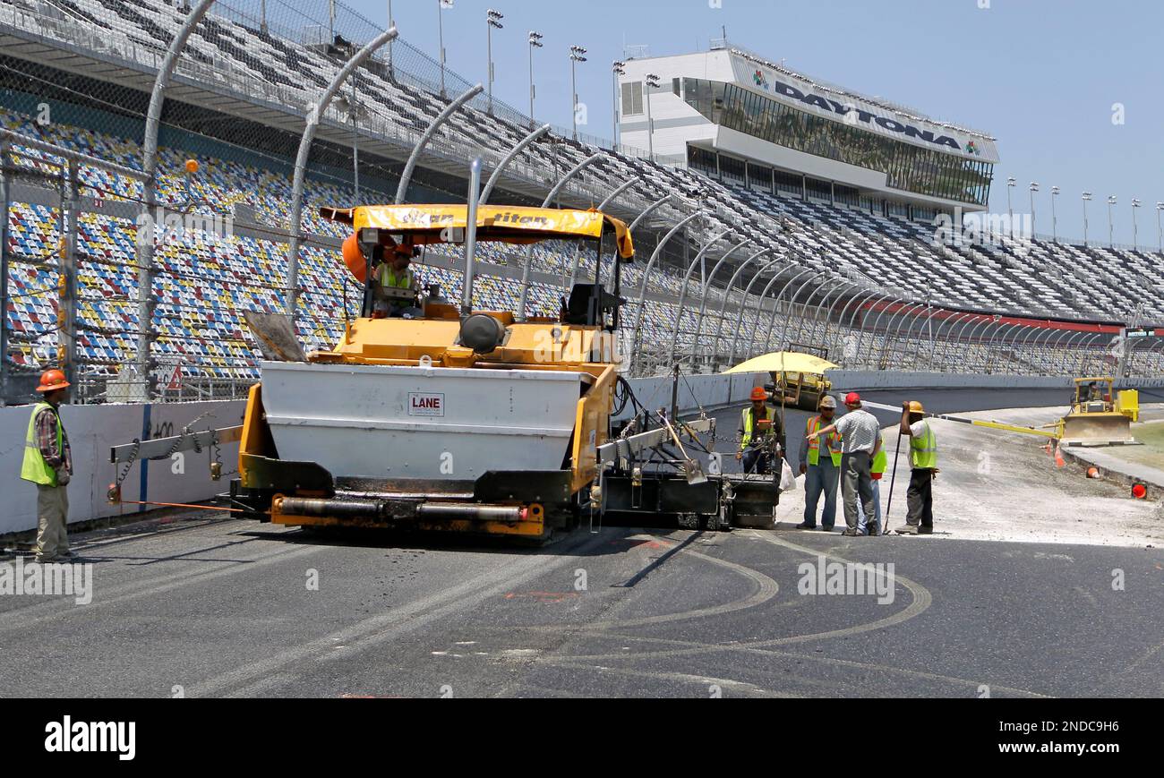 Paving equipment puts a layer of asphalt on the track surface during a ...