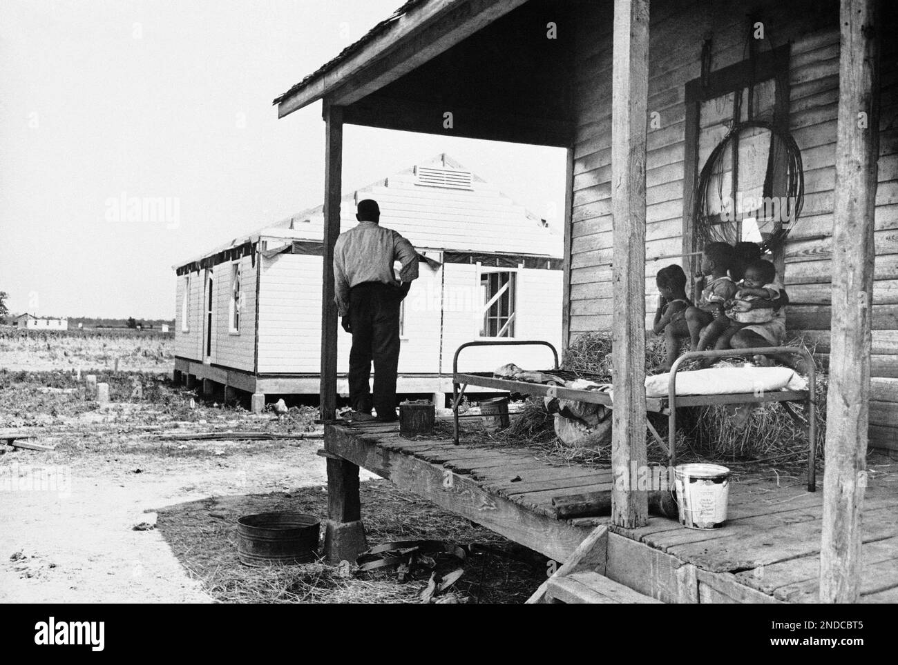 A sharecropper looks at his new home from the porch of his old shack in ...