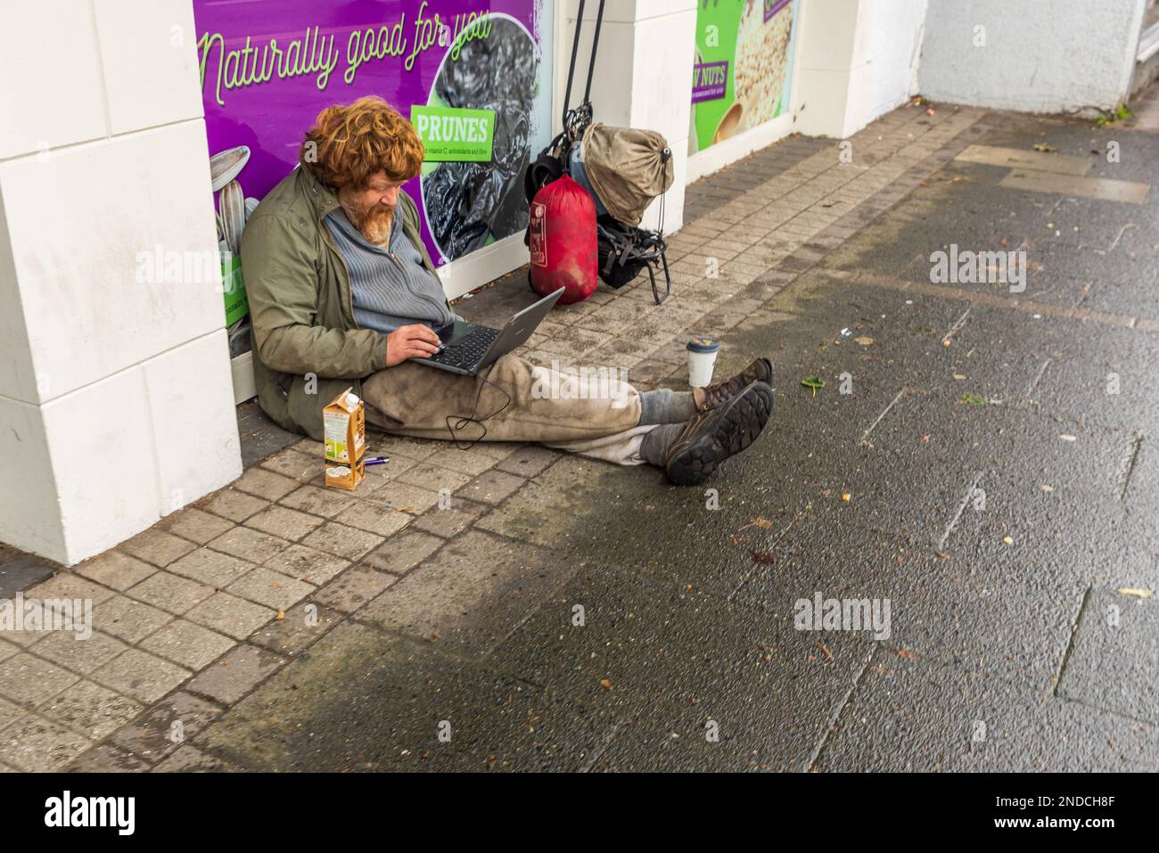 Homeless person sat on the floor with a laptop Stock Photo - Alamy