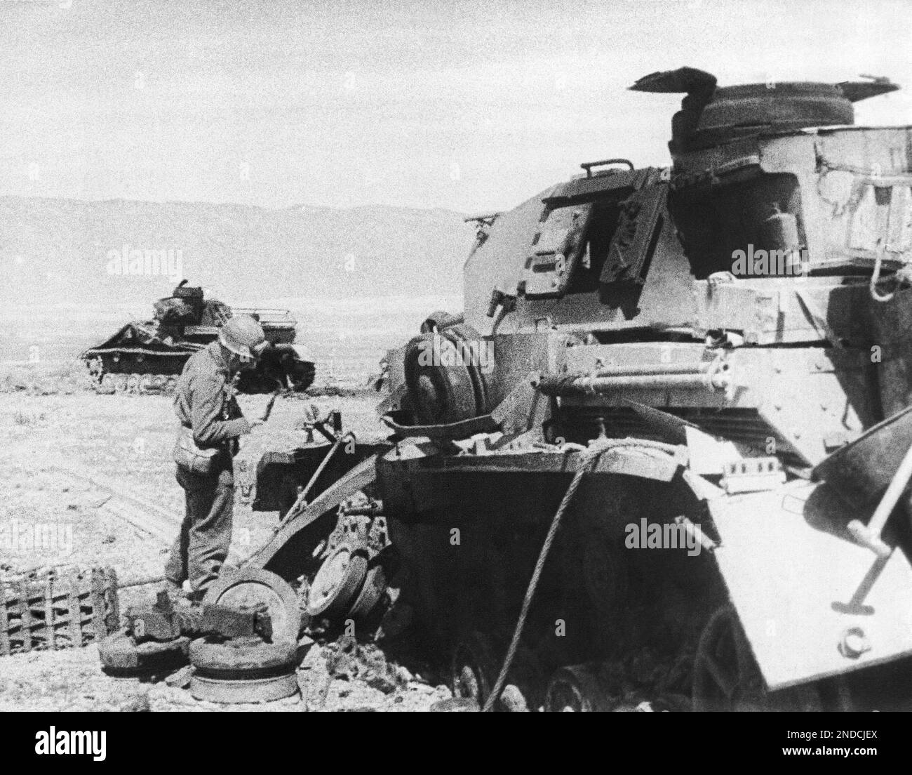 An Allied soldier inspects the wreckage of an Axis tank somewhere on ...