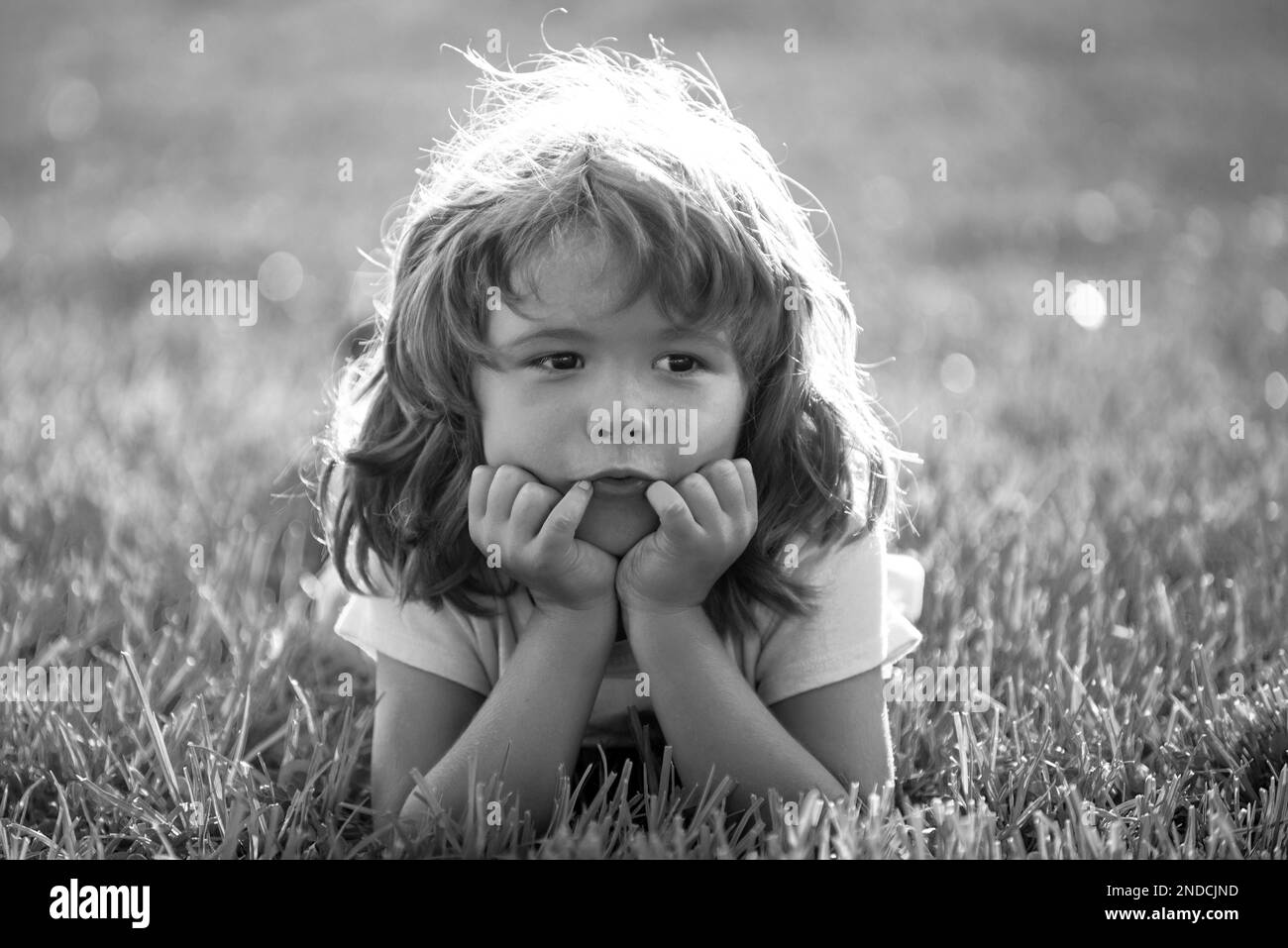 Child in park outdoor. Spring kid lying on grass. Summer boy walk ...