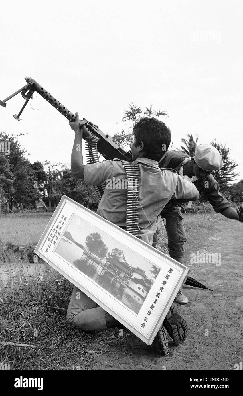 A Cambodian machine gunner and his bearer, right, struggle with a heavy ...