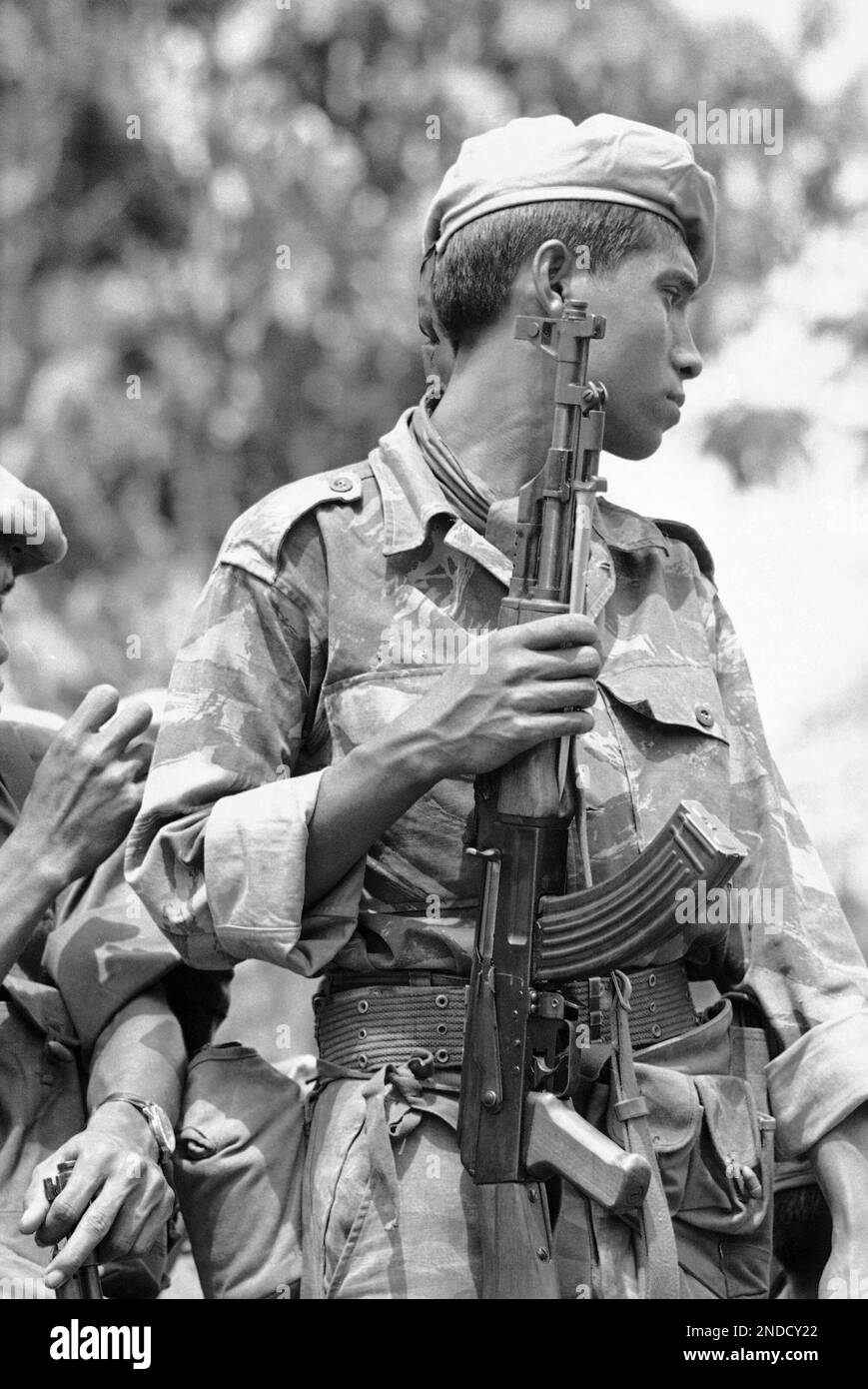 A Cambodian infantryman, armed with a rifle, sits grim-faced with ...