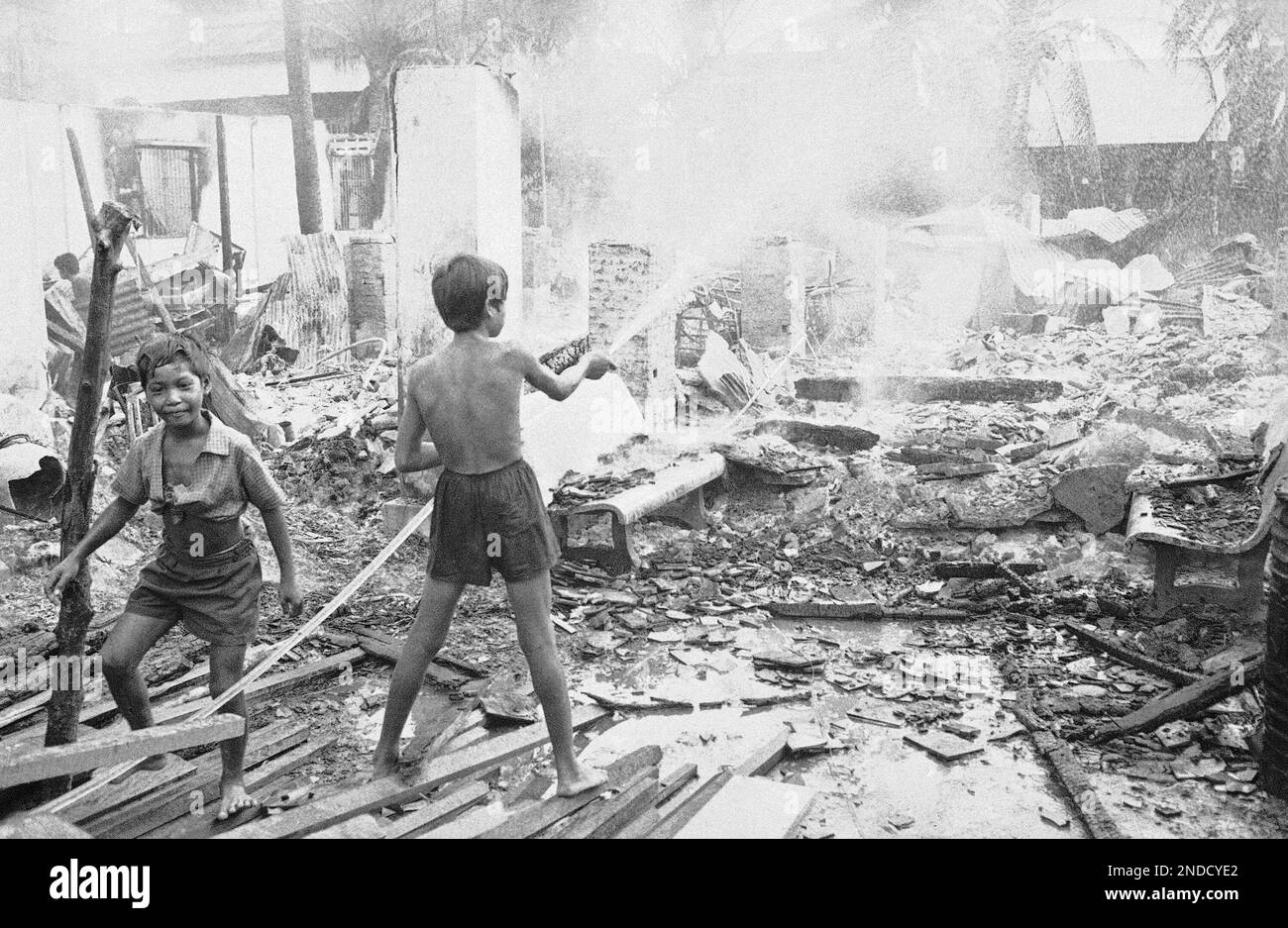 Cambodian youngsters use garden hose to douse smoldering ruins ...