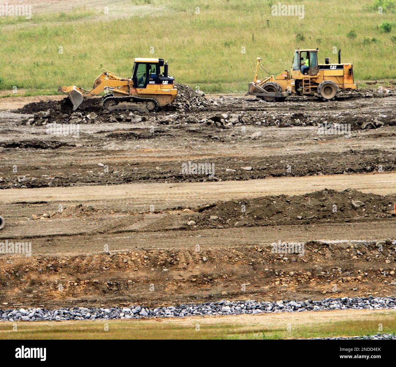 Earth moving machines move dirt around an excavation site while work ...